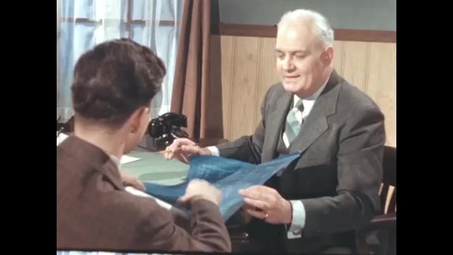 1940s: Loan officer and customer inspect blueprints and sign checks at ...