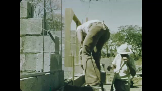 1970s: Construction worker laying cinder blocks over rebar. Worker ...