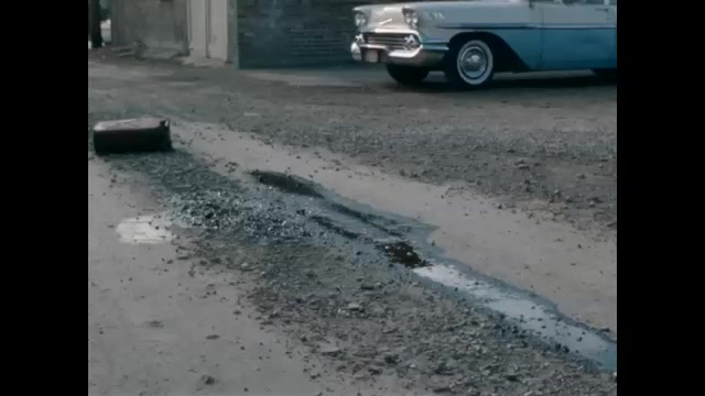1960s: Gas puddle in alleyway lights on fire. Man smothers fire with ...