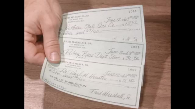 1960s: Hand holds checks. – Archival Footage
