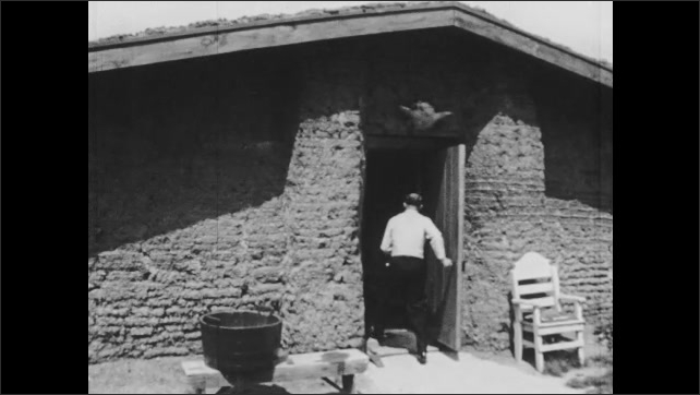 1960s: Farm field. Man picks up bucket and enters house with girl. Boat ...