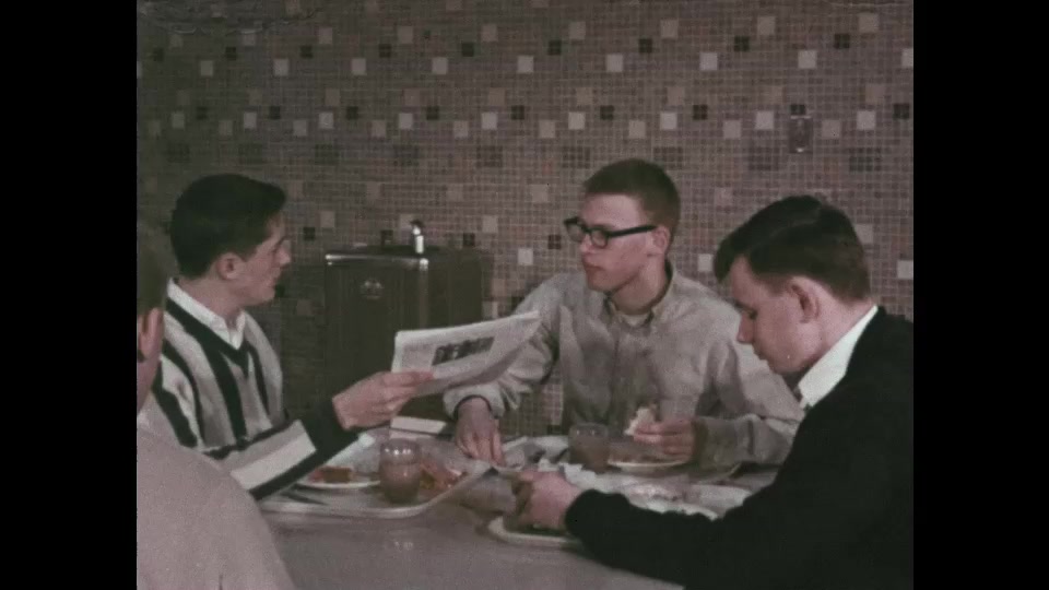 1960s: During school lunch, boy shows friend the newspaper. Kids talk ...