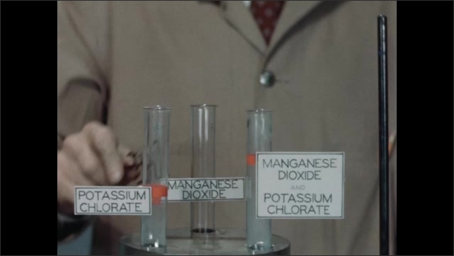 1940s: Man holds match over labeled test tubes in lab, zoom in, man ...