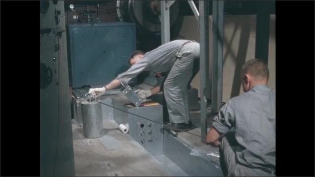 1960s: Hand holding chalkboard. Man removing cylinder from box with ...