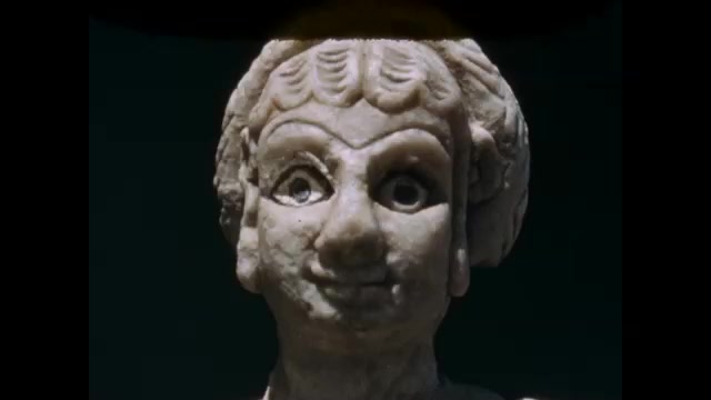 1950s: Ancient carved marble head with smile. Man building clay brick ...