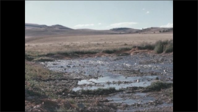 1960s: Water flows across land. View of dam. – Archival Footage