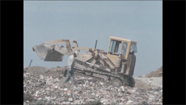 1950s: digger moves rubble at site. Dumper truck drives across rubble ...