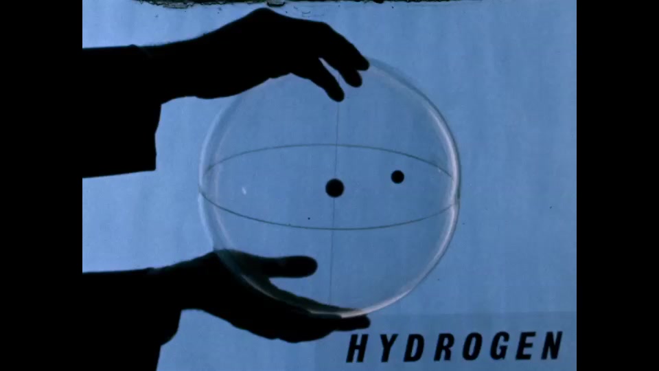 1960s: Silhouette of hands holding a model of a hydrogen atom ...