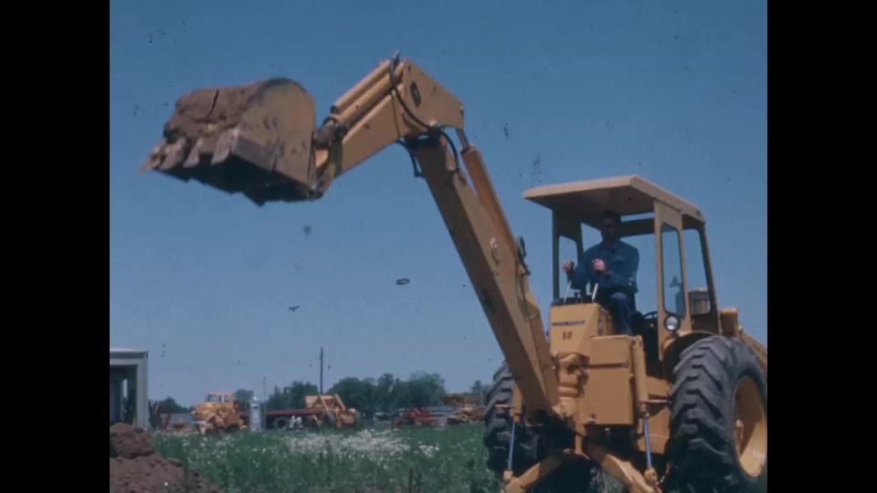 1960s: Backhoe digs in field. – Archival Footage