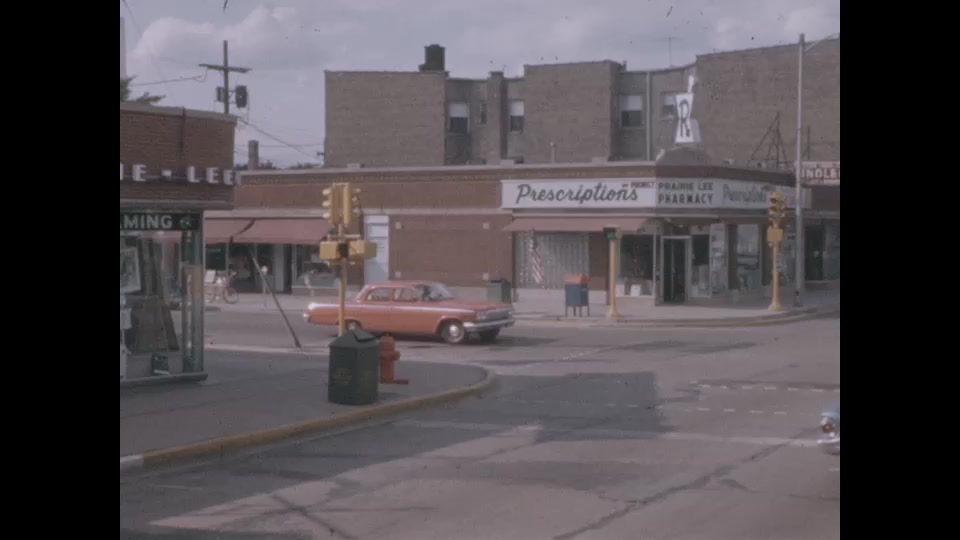 1960s: Cars and school bus drive through intersection on city streets ...