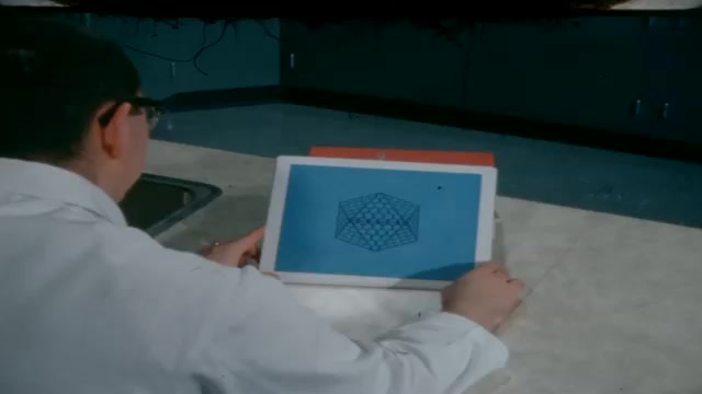 1950s: Man in lab coat sits at counter, looks at structural drawings of ...