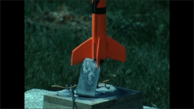 1960s: Boy launches a model rocket in a field. The base of a model ...