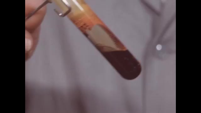 1940s: Person swirls test tube over bunsen burner. – Archival Footage