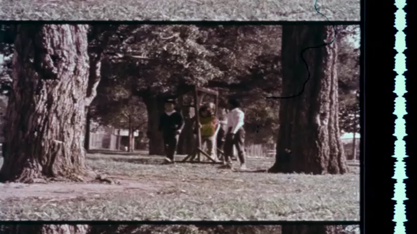 1970s: Kids push wooden frame through park. Kids run to frame and ...