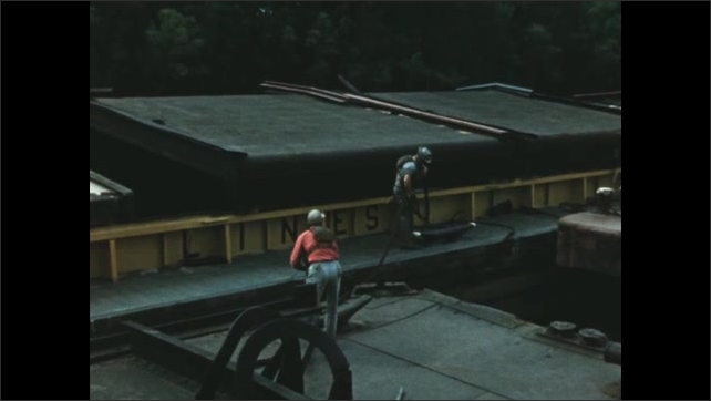 1950s: Tugboat pulls ship out into river. Men secure barges to dock ...