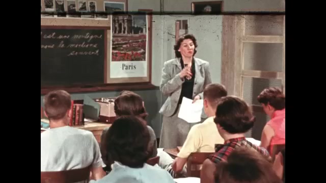 1950s: Teacher speaking to the class, zoom into poster of France ...