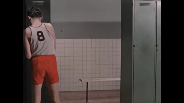 1950s: Teenage boy takes object from locker in locker room and hides it ...