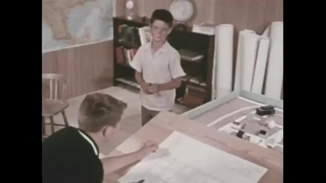 1960s: Boys look at map. Man draws line on street. Man draws symbol for ...