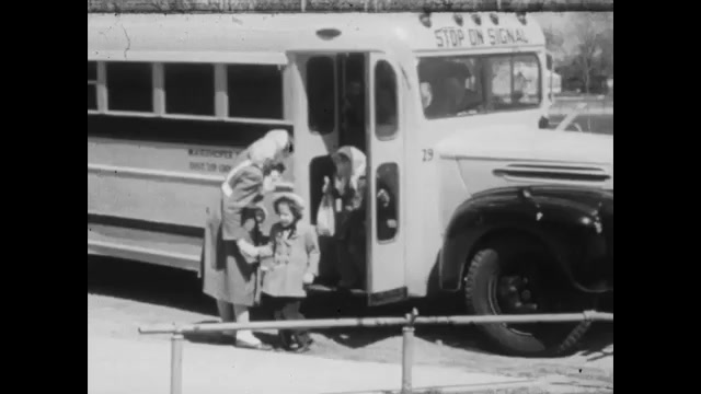 1950s: Children exiting the school bus. Girl explaining her map to the ...