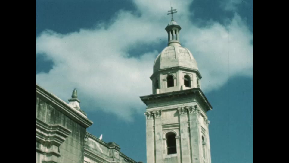 1960s: Church tower. Bird flies. People walk around building ...