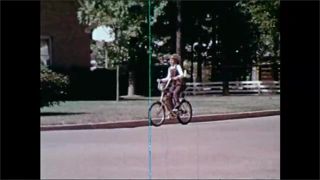 1970s: Girl bicycles down street, signals a right turn, looks behind ...