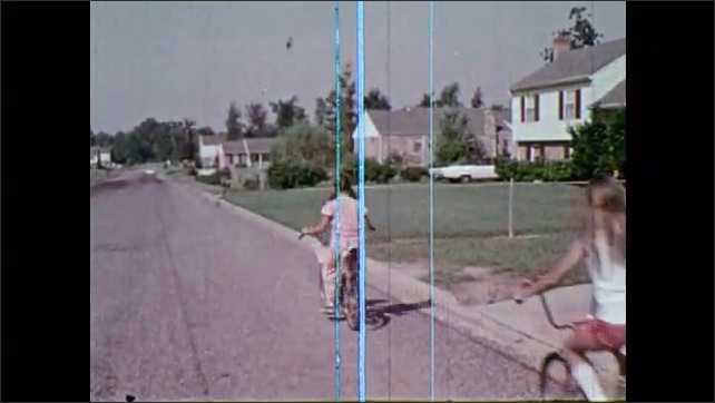 1970s: Children ride in a single file line down street. Girl rides ...