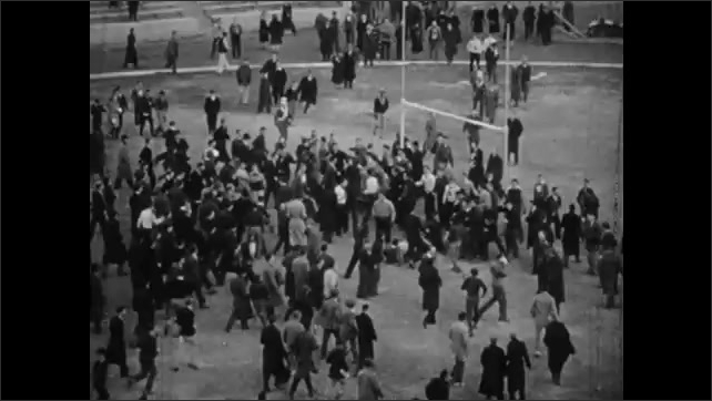 1940s: Crowd on football field. Men fight. – Archival Footage