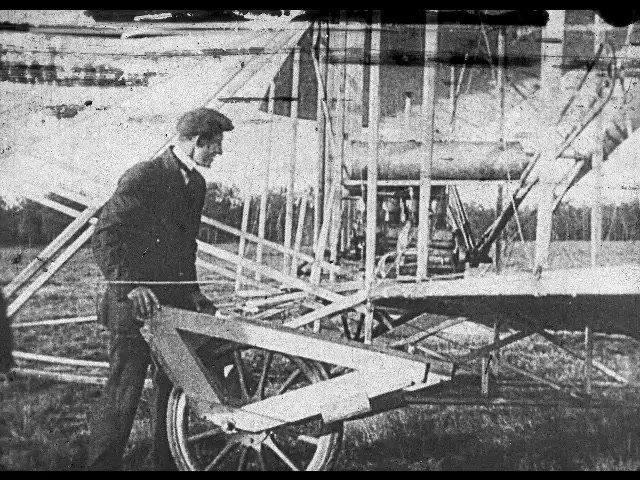 1920s: Man affixes wheel to bottom of wing of Wright brothers’ plane ...