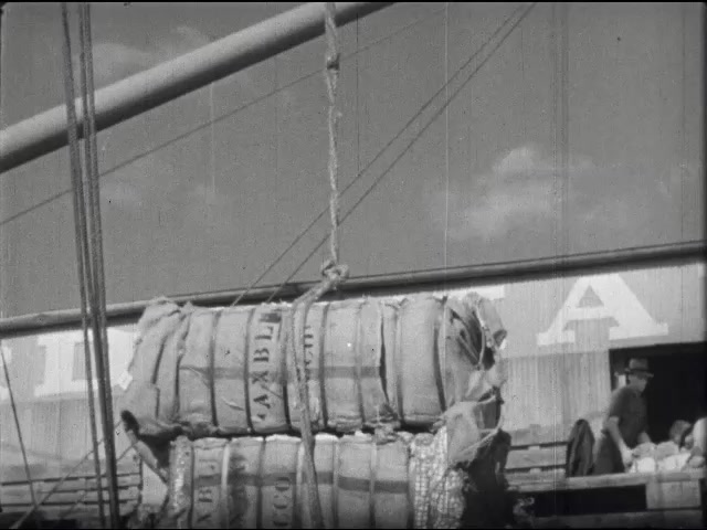 1920s: Men load cargo. Ships. City. River. Bridge. – Archival Footage