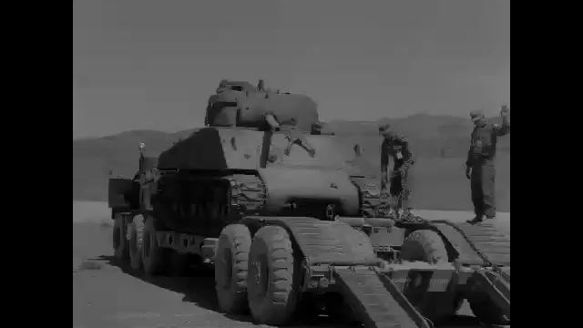 1950s: Soldiers unload tank from trailer. Soldier drives military ...
