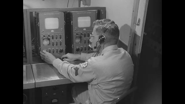 1950s: Soldiers work in television studio control room. Man speaks and ...