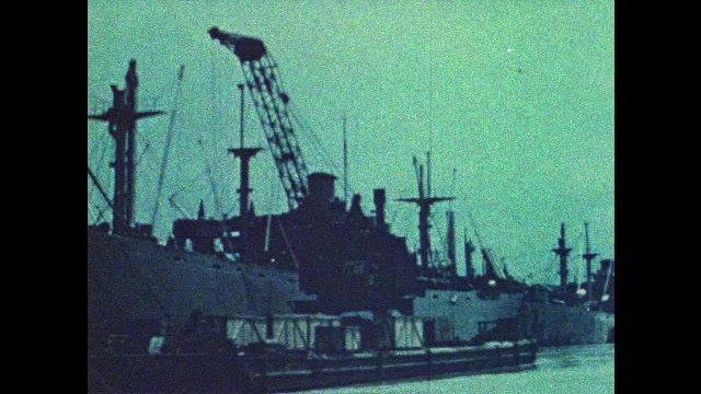1940s: Line of cargo and troop ships float in harbor. Names emblazoned ...