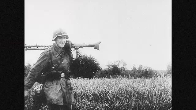 1940s: Soldiers march down dirt road. Soldier camouflages helmet with ...