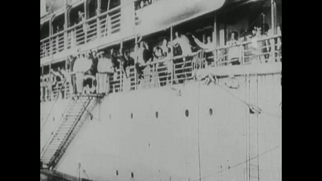 1910s: People wave goodbye as ship leaves dock. Men shoot weapons from ...