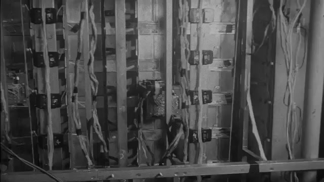 1950s: Miniature elevators moving up and down. Man looking into cabinet ...