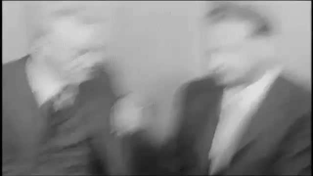 1950s: Two men at table surrounded by reporters. Two men leave room ...