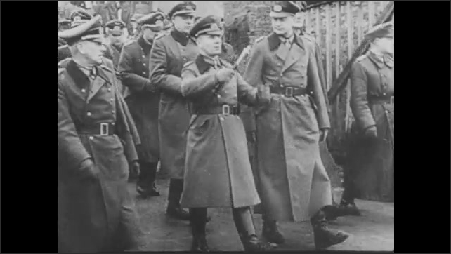 1940s: Nazi officers walk around fortifications. Barbed wire and other ...