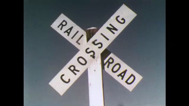 UNITED STATES: 1970s: railway crossing sign. Car approaches junction ...
