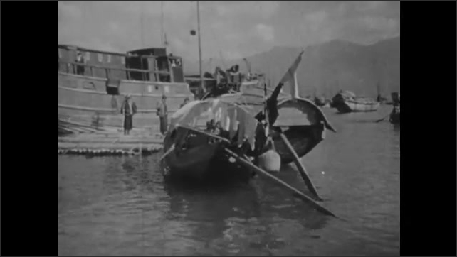 1940s: CHINA: sailor hoists sail on boat in China. Crowded harbour with ...