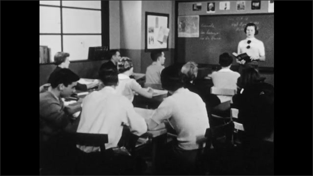 1950s: High school classroom. Teacher speaks. Group of boys talk and ...