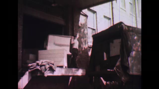 United States: 1950s: Men move large box into van. Train transports ...