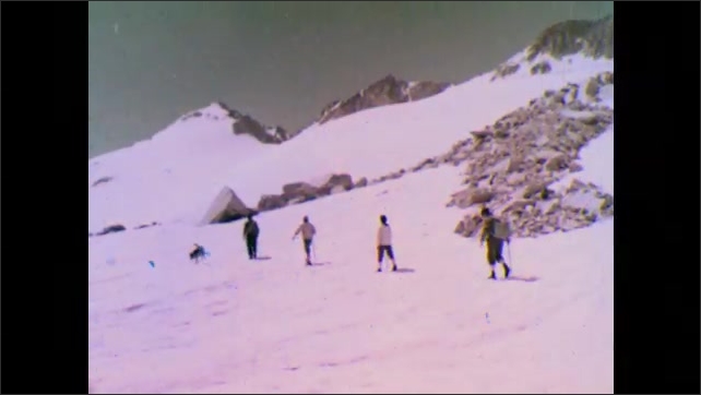1950s: Mountains. Hikers and dog walk through snow. – Archival Footage