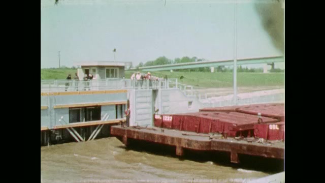 1970s: towboat pushes barges into canal waterway lock as men look on ...
