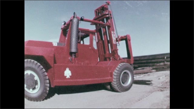 1970s: Two red lift trucks move in yard. Forklift stops and lifts a ...