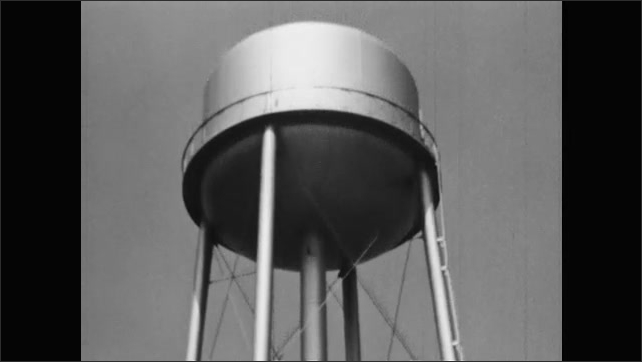 1950s: Pan of water tower. Workers lower pipe into ground. – Archival ...