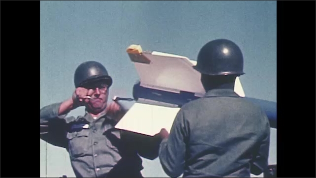 1960s: Laboratory experiment. Two soldiers mount missile. Engineer ...