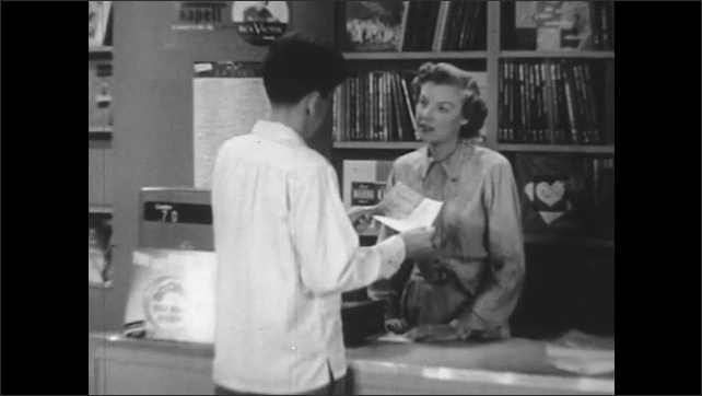 1950s: Teen boy speaks to woman at service counter in record store. Boy ...