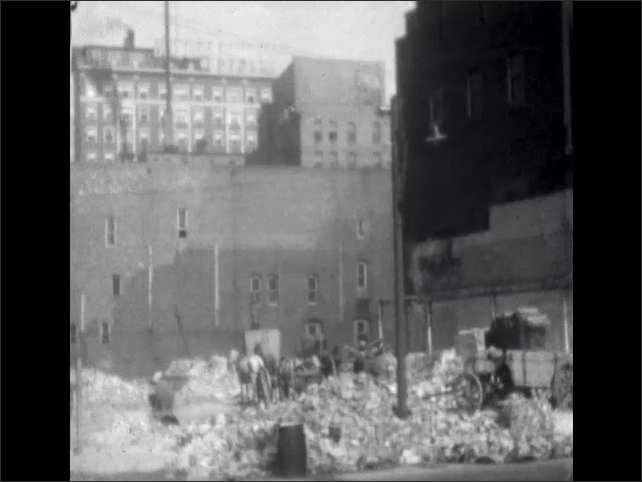 1920s: Men work near piles of bricks and wagons of construction ...