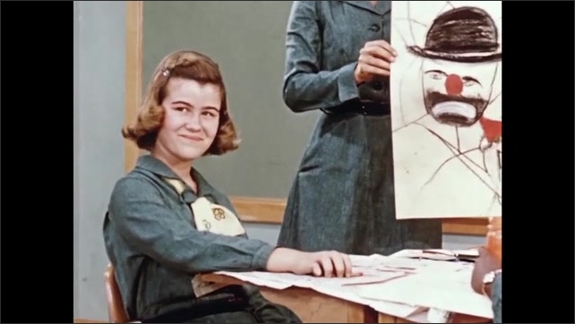 1950s: Girl Guides drawing in class. Leader checks on girl and shows ...