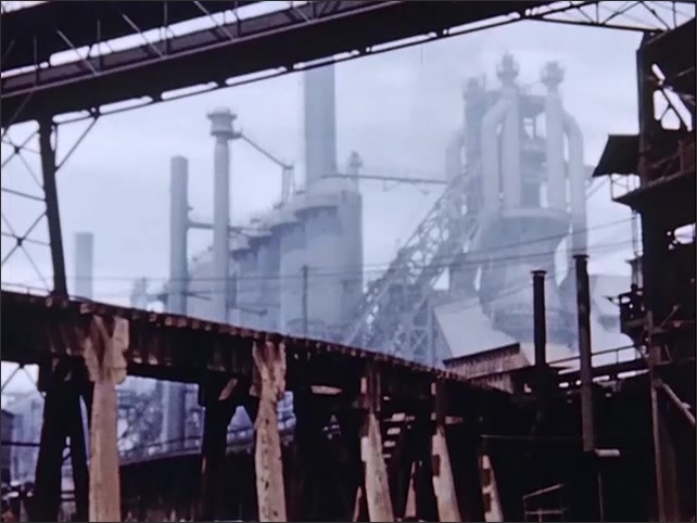 1940s: Smokestacks stand near industrial plant. Cranes load materials ...